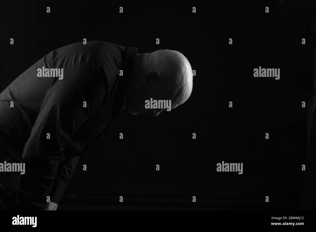 desperate and bending man on black background Stock Photo - Alamy