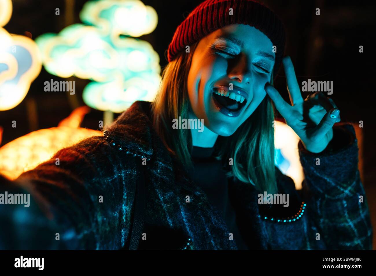 Photo Of Joyful Woman Gesturing Peace Sign And Taking Selfie Photo