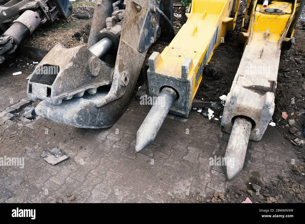Heavy chisels and concrete shears as excavator attachments lie side by ...