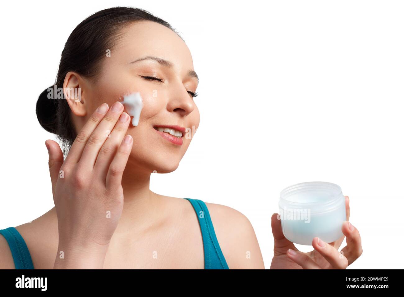 Happy smiling beautiful woman applying moisturizer cream on the face ...