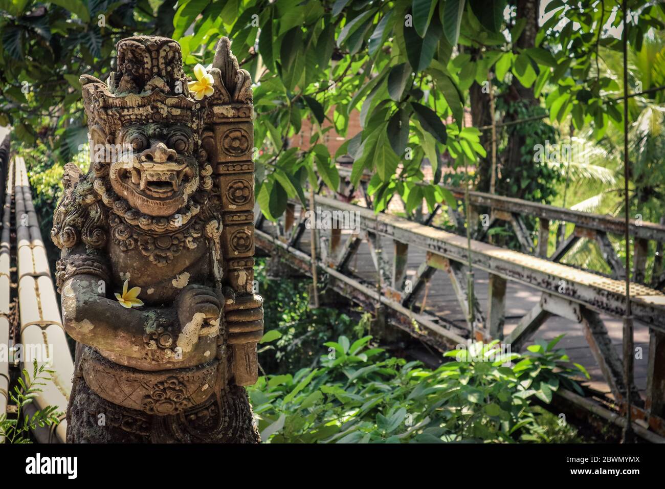 Traditional Balinese guardian statue near old wooden bridge in Ubud ...