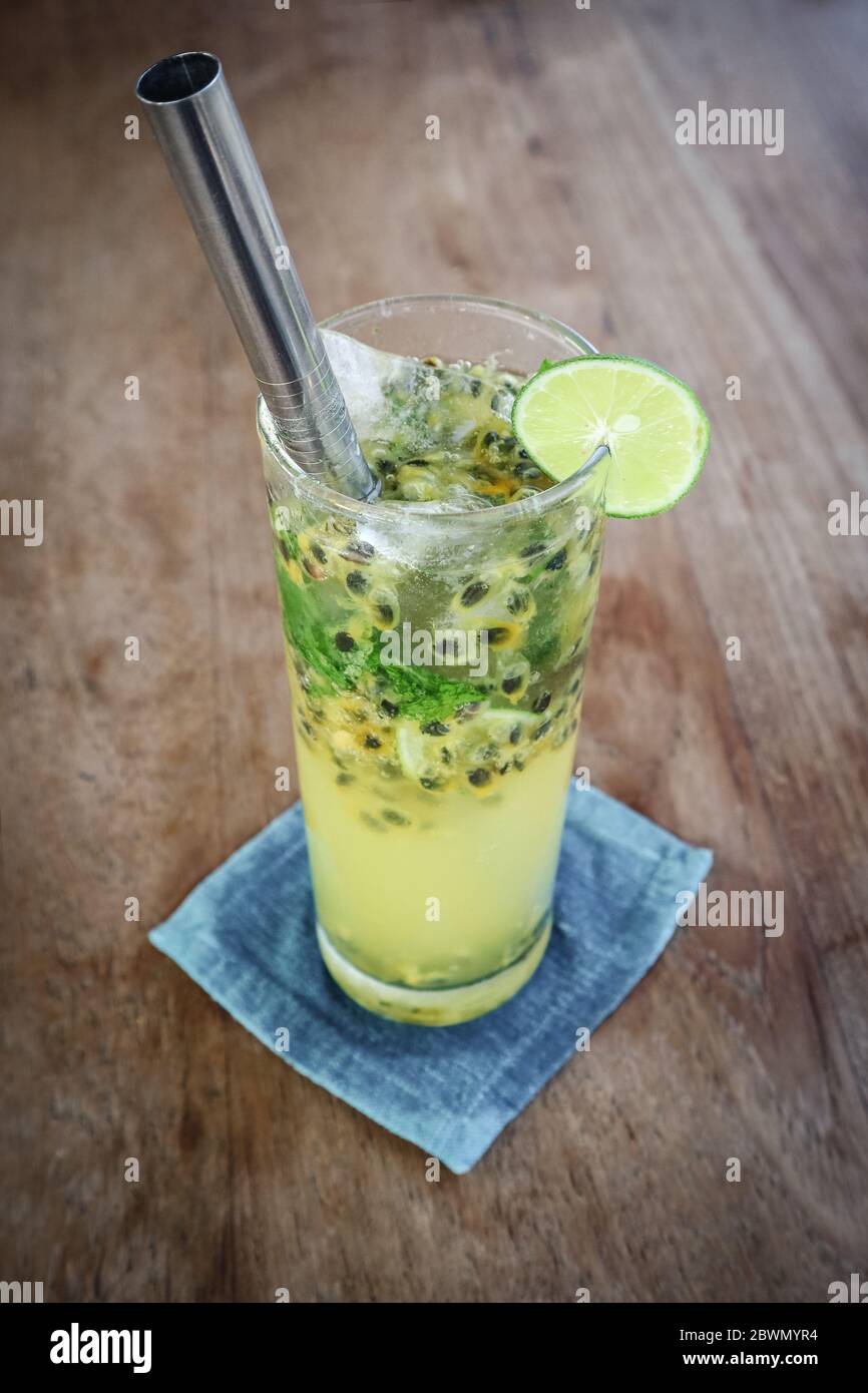 Passion fruit mojito cocktail with metal drinking straw on wooden table ...