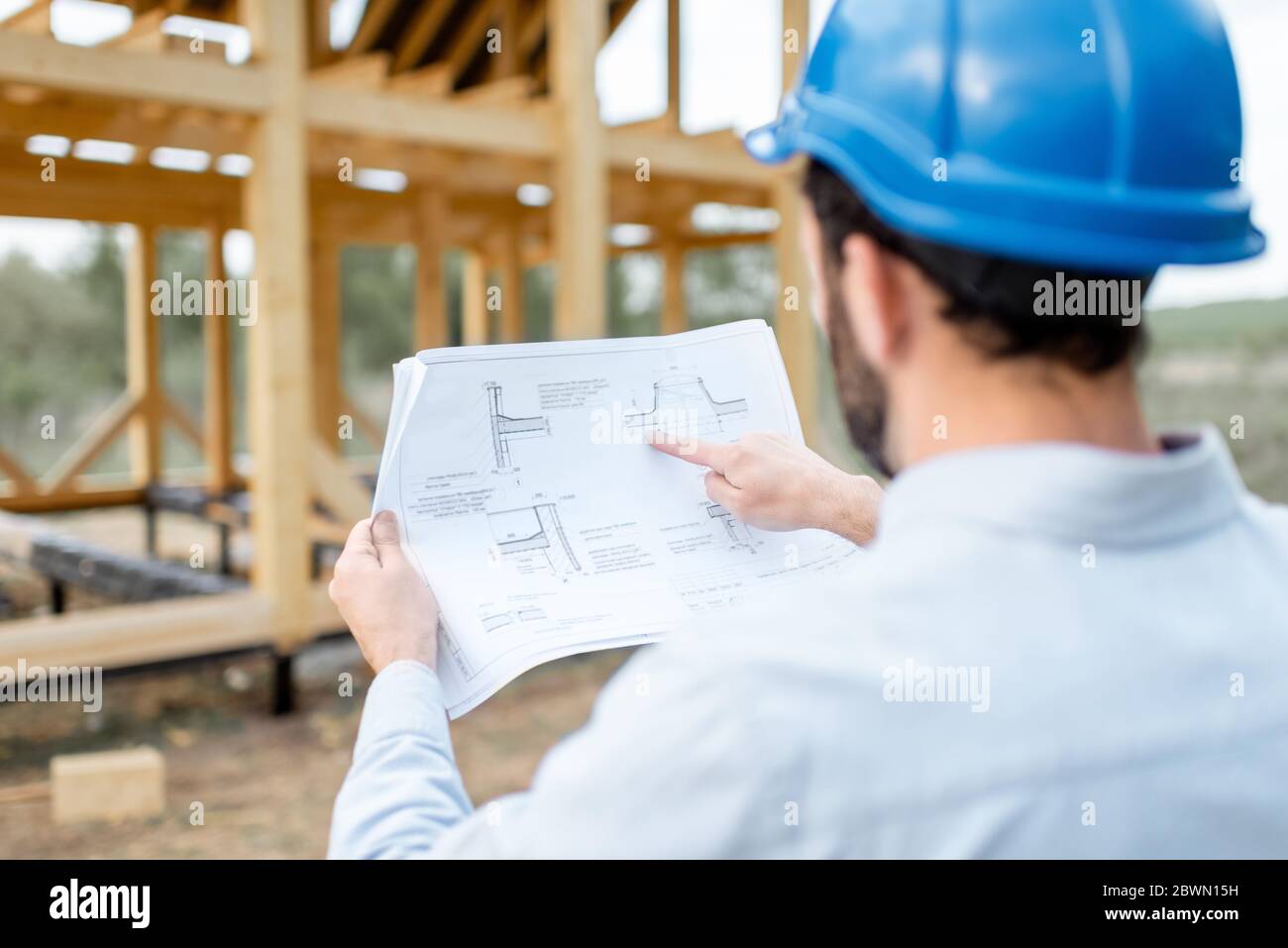 Builder looking on teh drawings of wooden house structures on the ...