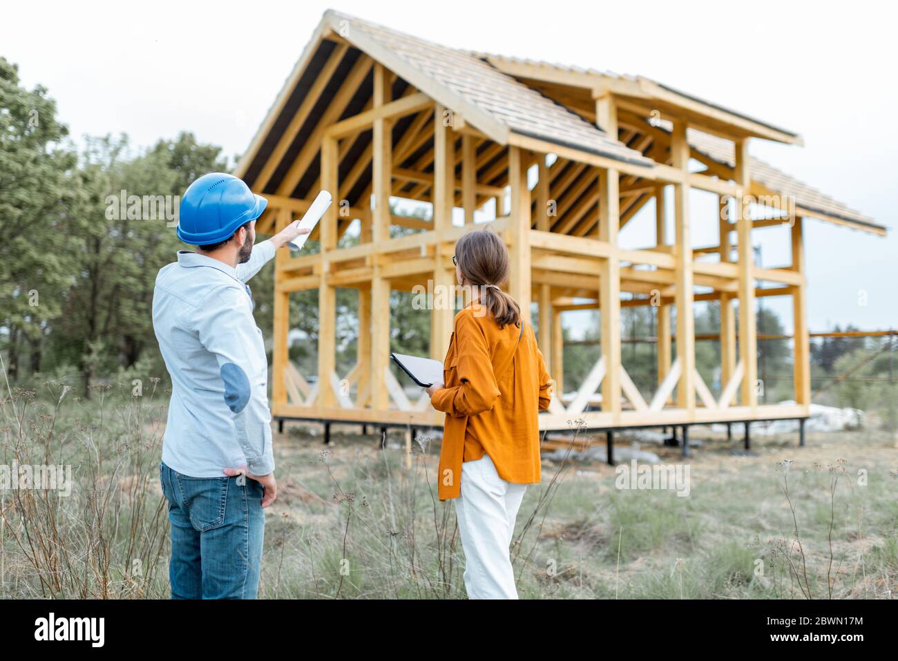 Builder with a female client near the wooden house structure on the ...