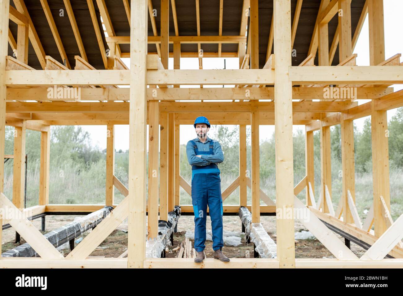 Builder in blue overalls and hard hat on the construction site ...