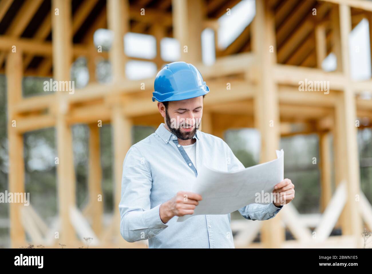 Builder or architect in hard hat supervising a project, standing with ...