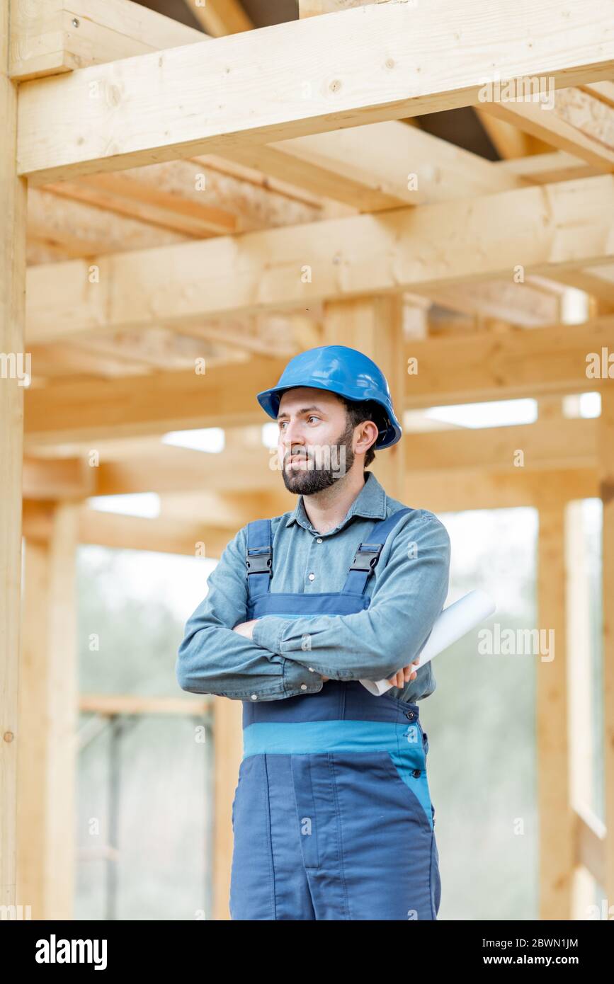 Portrait of a handsome and cofident builder in blue overalls and hard ...
