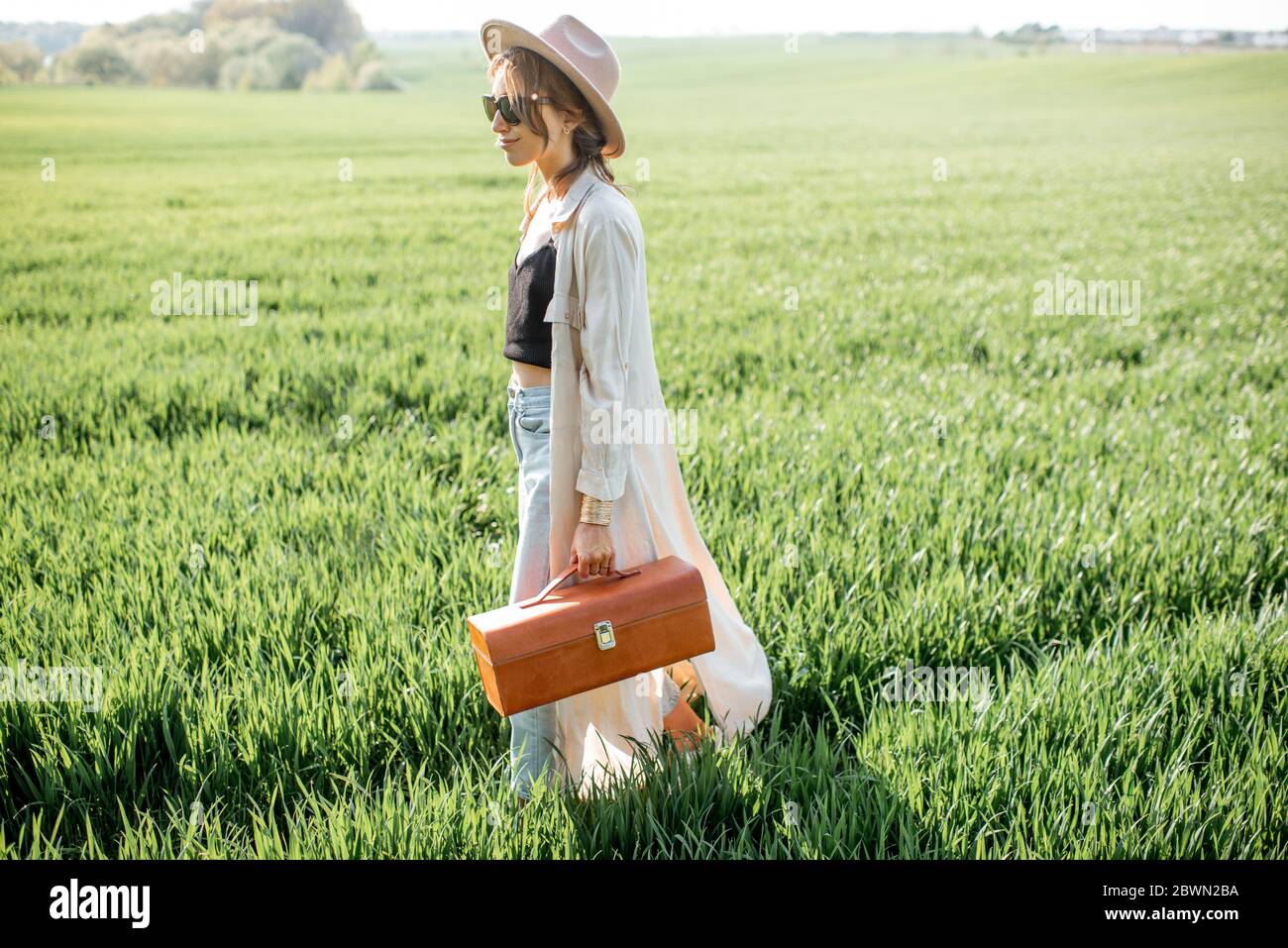 Portrait of a stylish woman walking with handbag on the greenfield ...