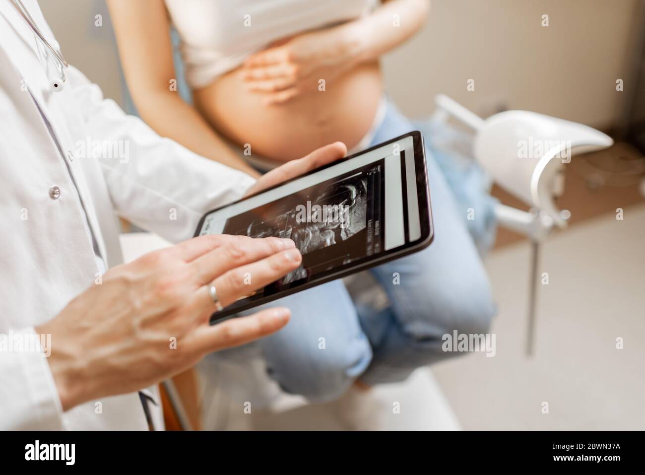doctor with an ultrasound scan of unborn child on a digital tablet ...