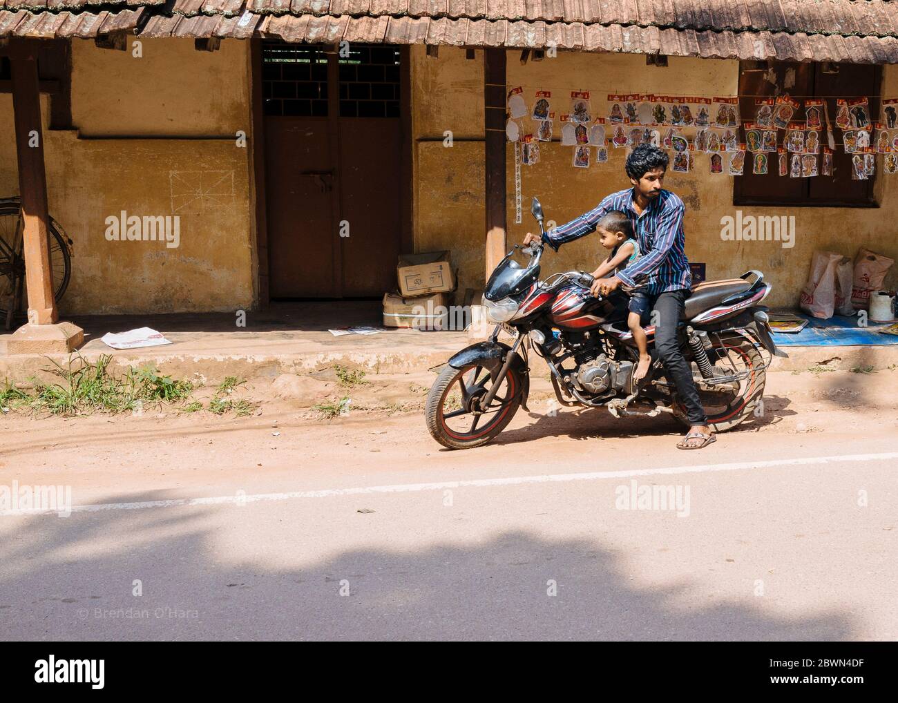 Man rides motorcycle with small boy on lap Stock Photo - Alamy
