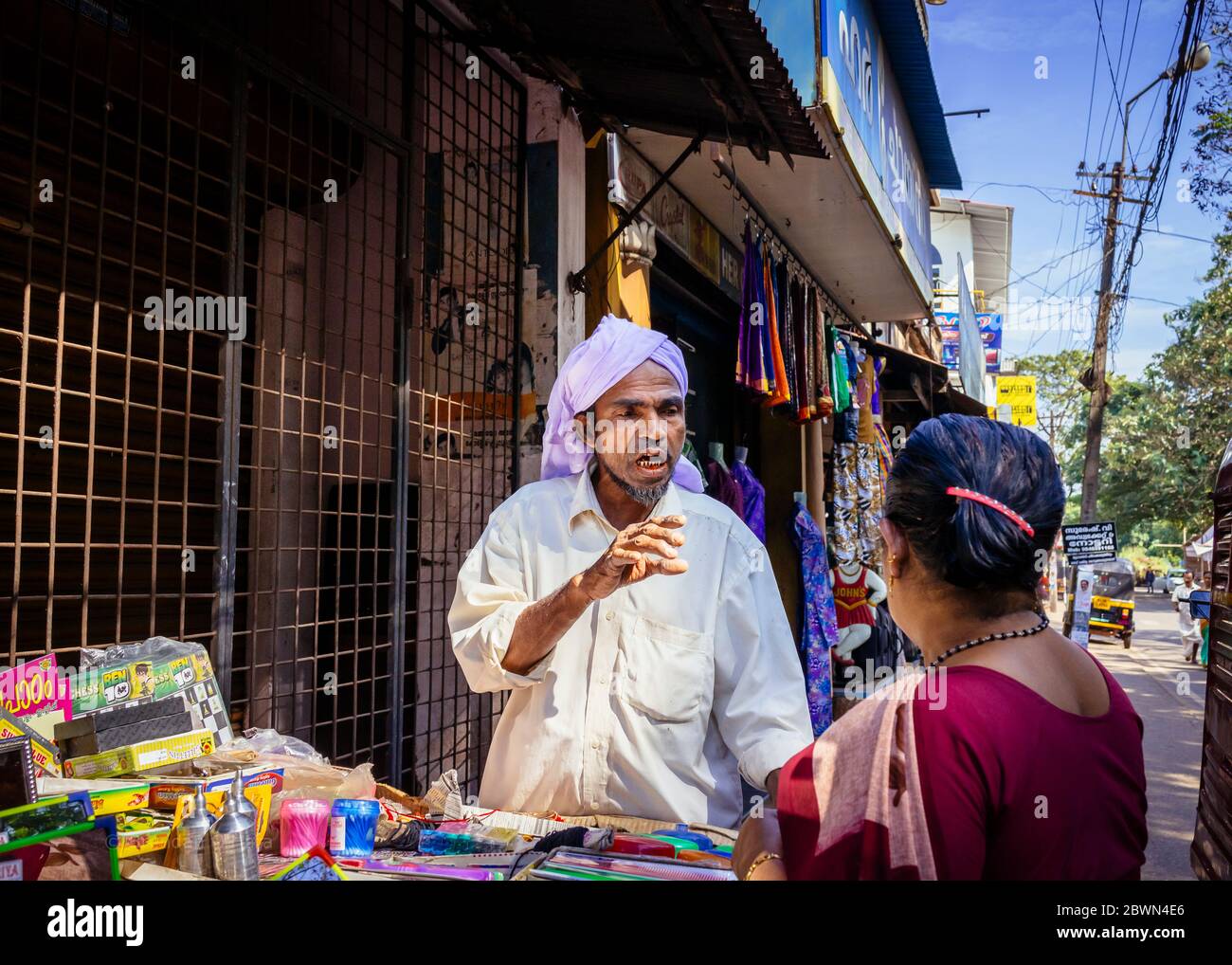 Male vendor speaks with female customer at curbside at storefront in ...