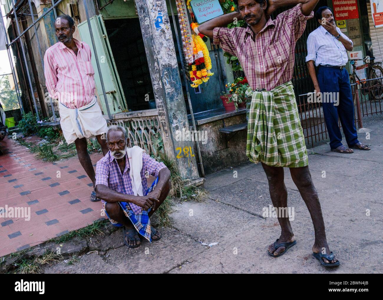Four men wearing plaid and striped western shirts and Lungi, stand ...