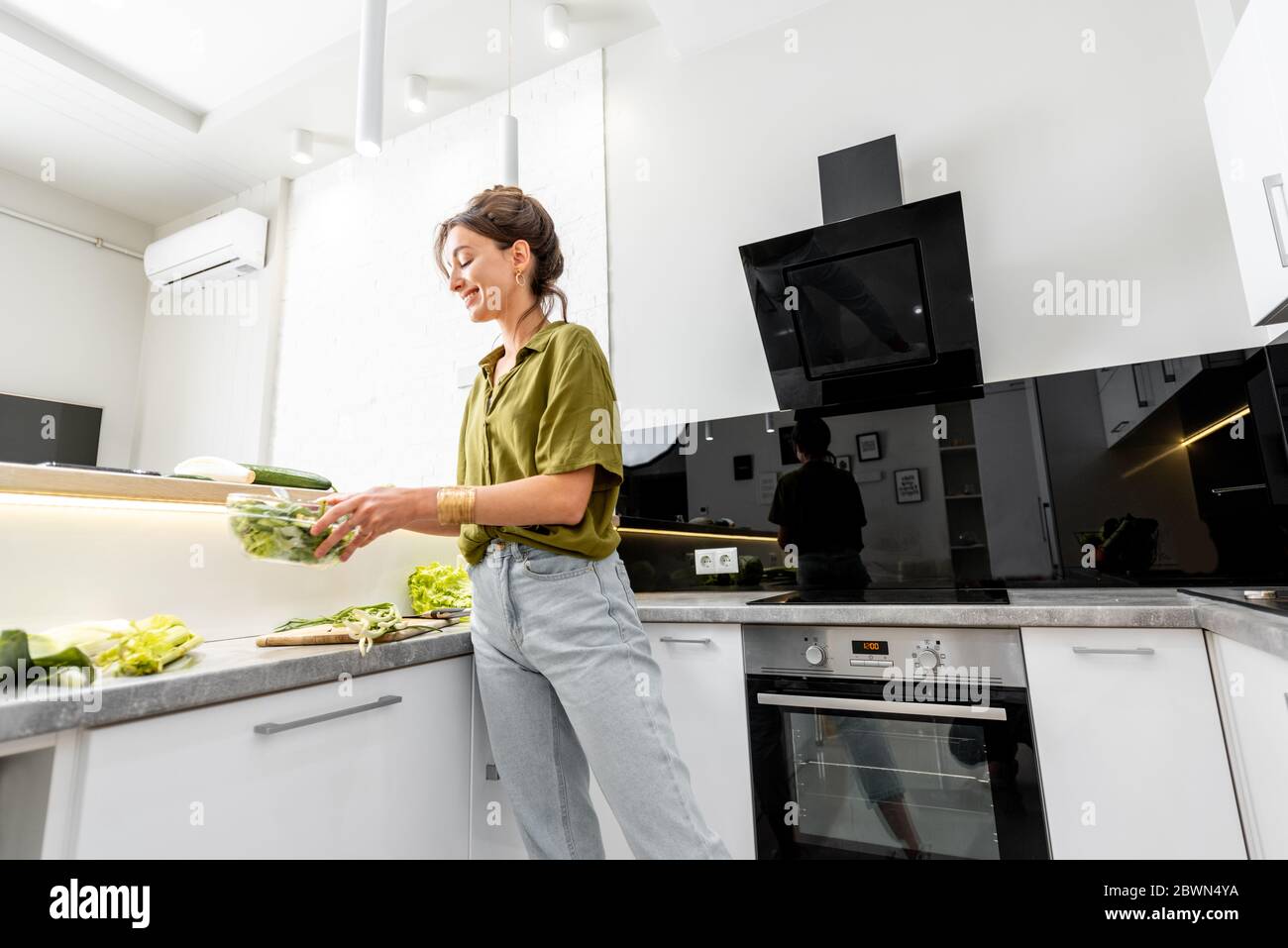 Woman cooking healthy food on the modern kitchen at home, wide intreior ...