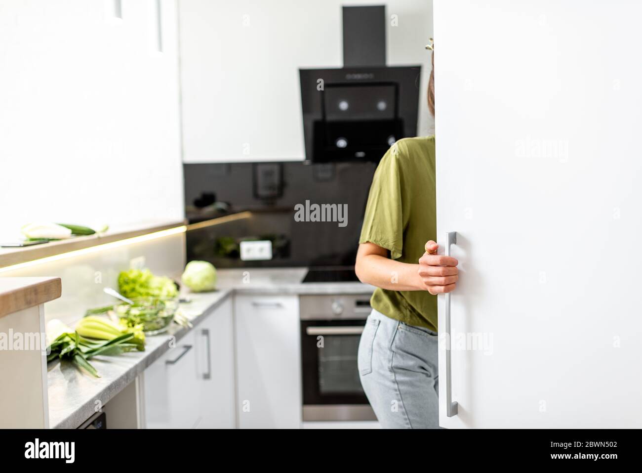 Woman looking into the fridge while cooking healthy food on the modern ...