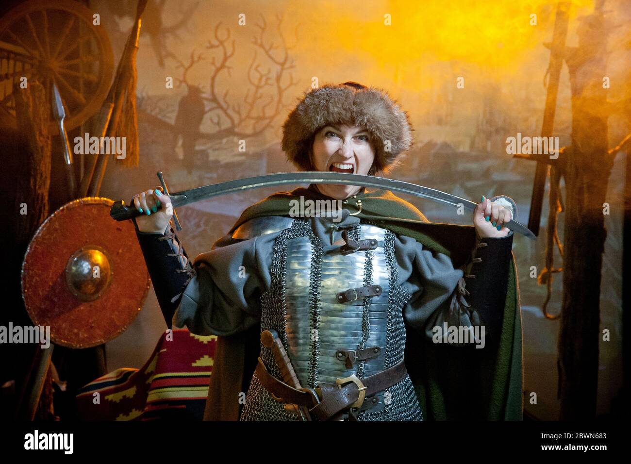 A woman biting scimitar dressed in chain mail, cloak and fur hat ...