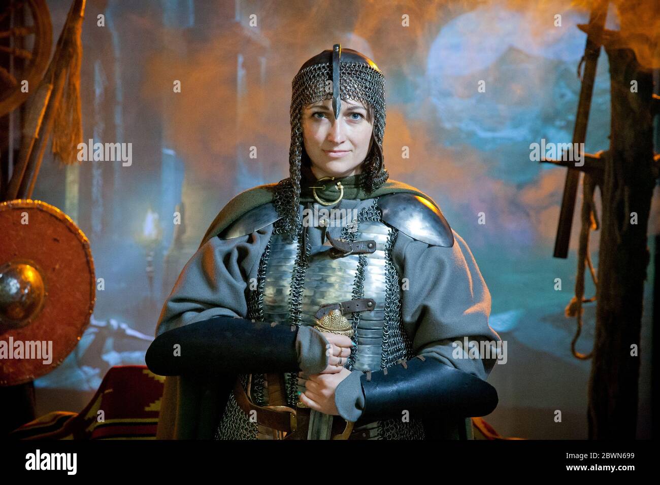 A woman dressed in chain mail with a sword in her hands against the ...