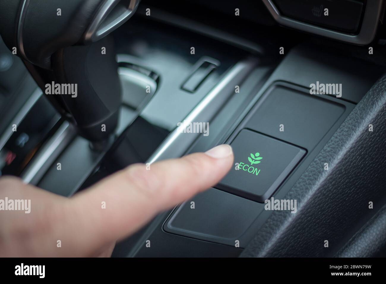 Finger pressing econ button in car dashboard. Reducing fuel consumption ...