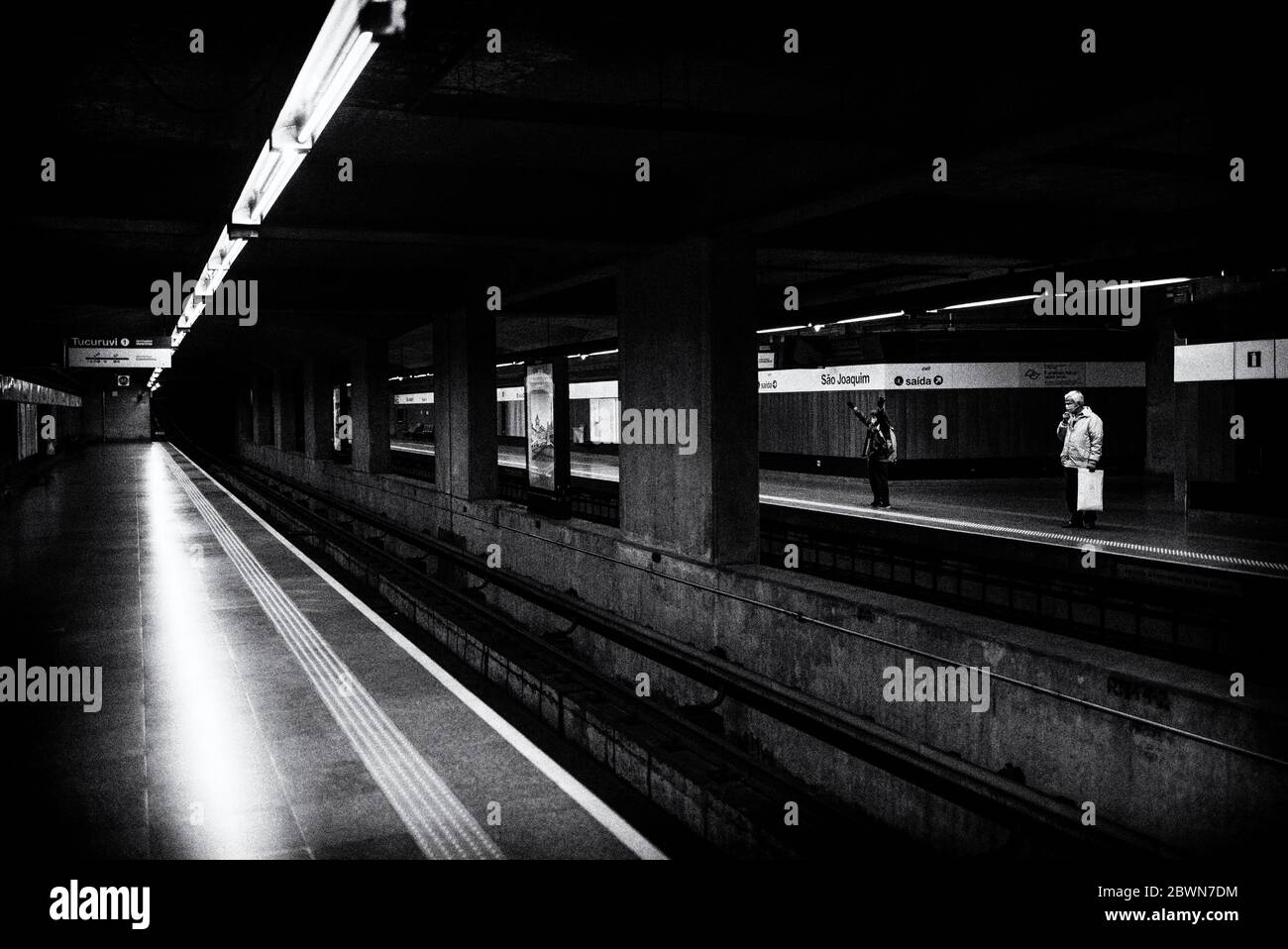 Two persons standing up alone in a dark station Stock Photo - Alamy