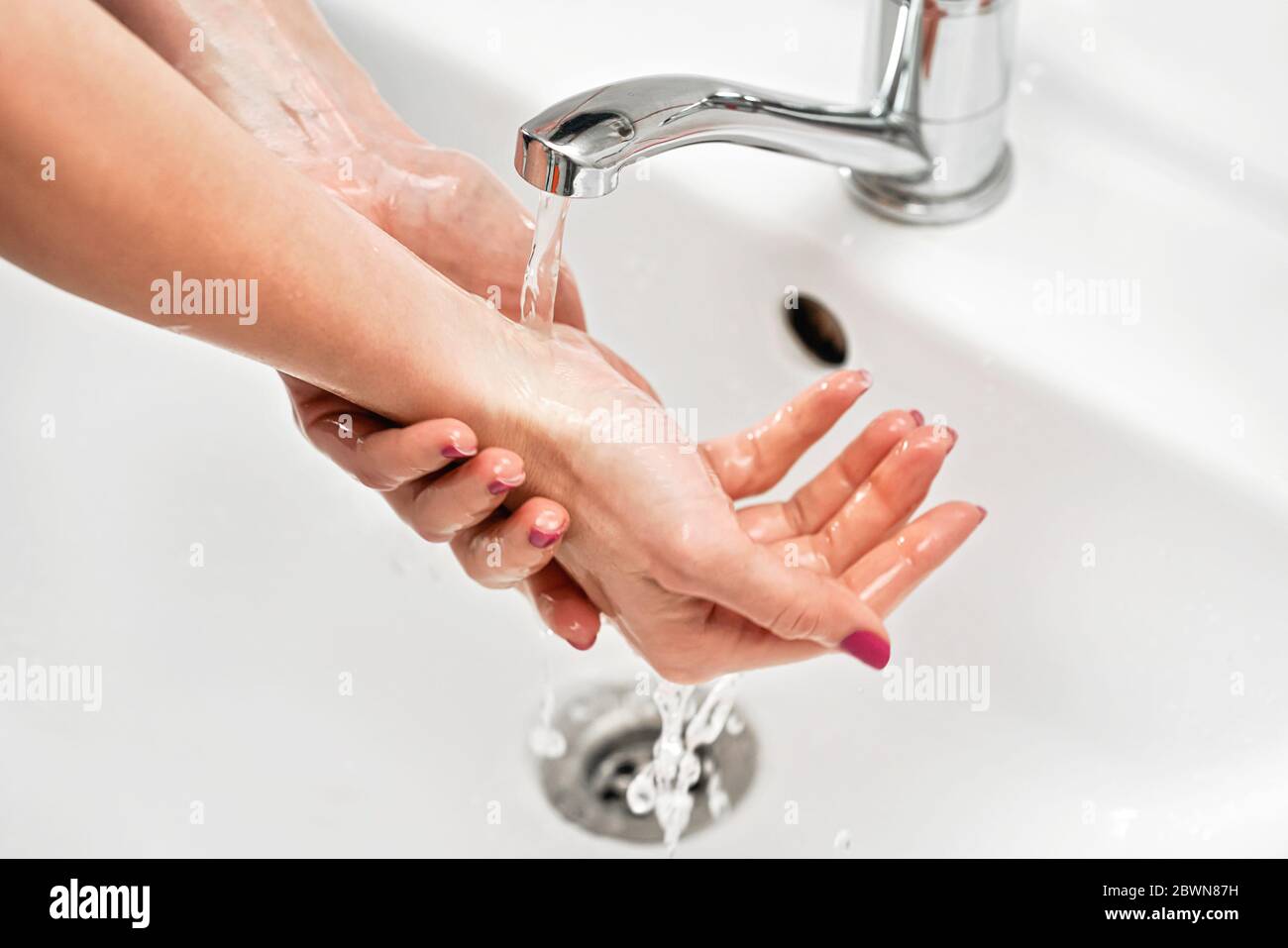 Young woman washing her hands under water tap faucet. Detail on liquid ...