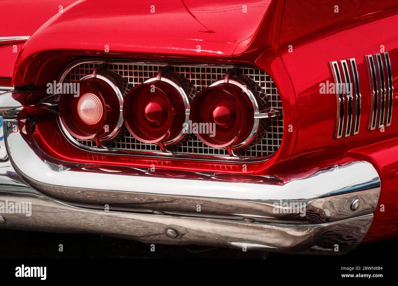 Rear part of exterior of a red old timer luxury sports car with tree ...