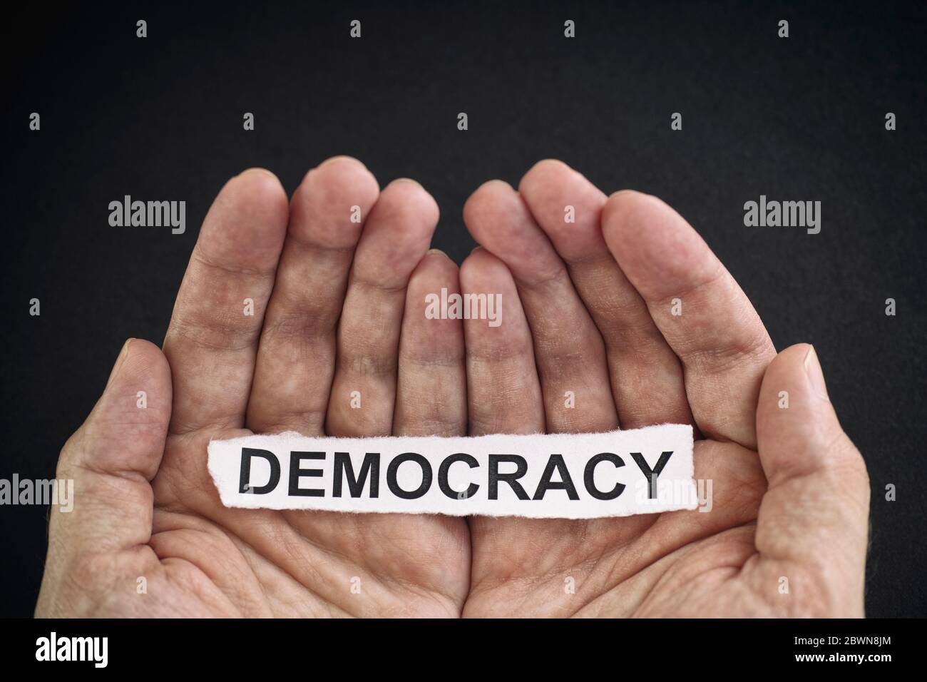 Man holding piece of paper with the word Democracy in his hands. Close ...