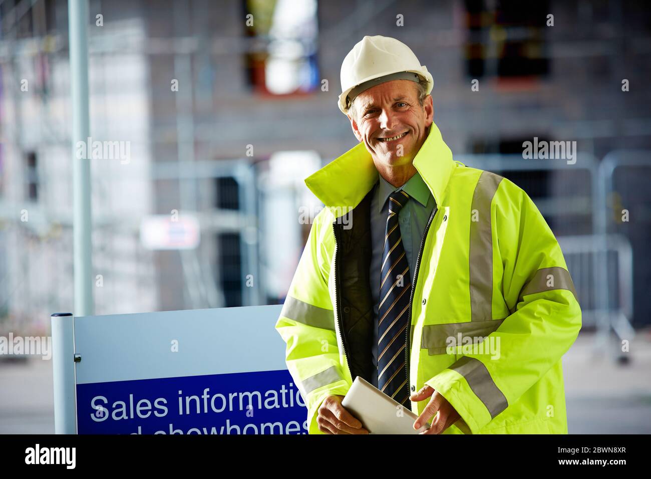 Portrait of smiling mature architect wearing a hardhat and reflective ...