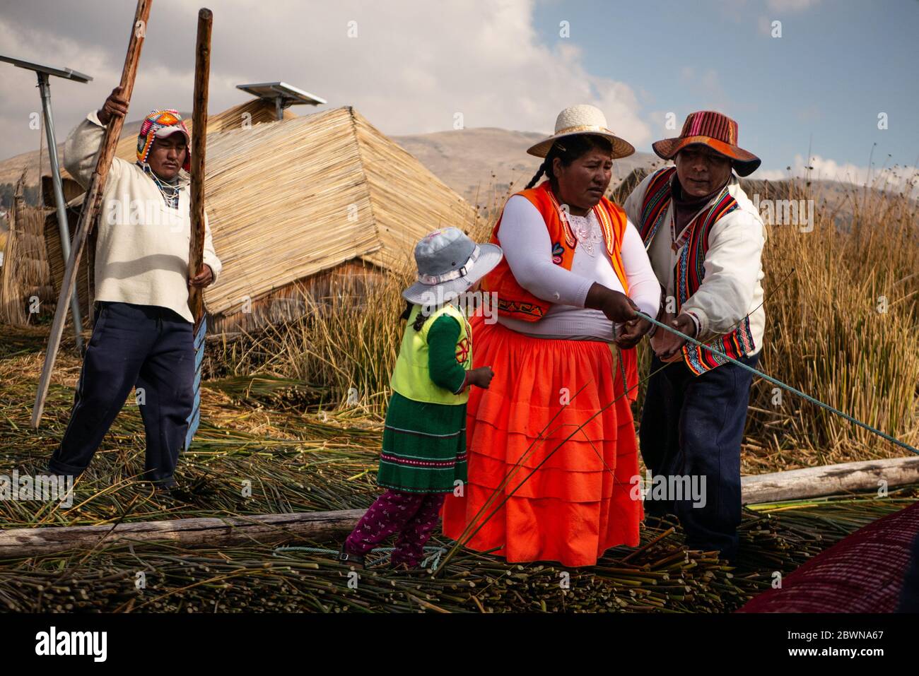The Uros indigenous family help to unmoor the traditional boat made of ...