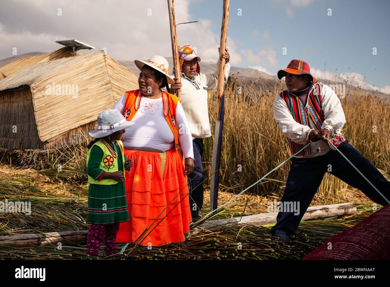 The Uros indigenous family help to unmoor the traditional boat made of ...