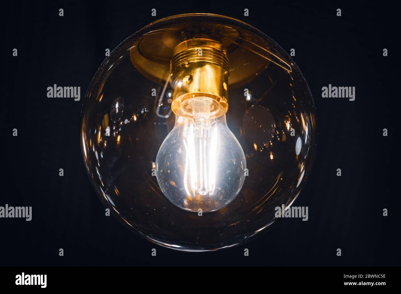 Giant vintage style light bulb lit with its retro filaments visible ...