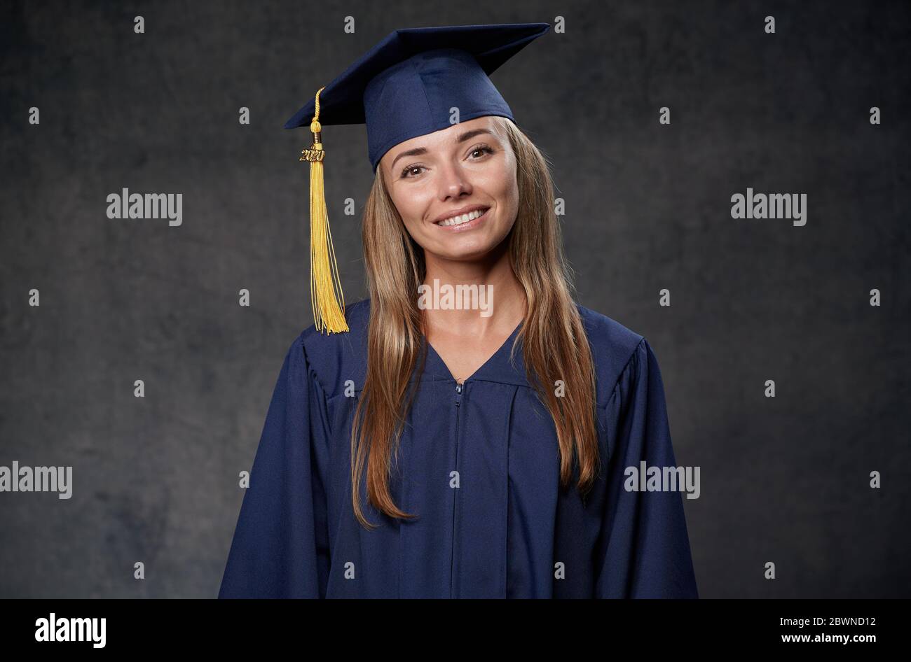 Happy female graduate wearing blue cap and gown looking straight Stock ...
