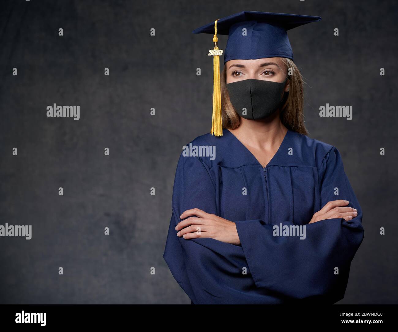 Young woman graduate in black mask with hands crossed celebrating her ...