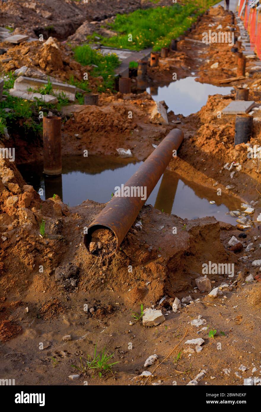 Rusty iron tube laying in mud. Construction works. Vertical shot Stock ...