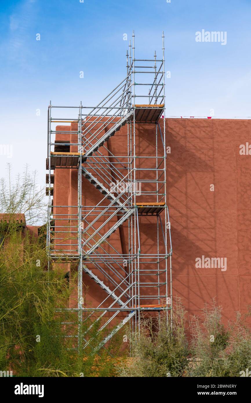scaffolding on the side of a red stucco building Stock Photo - Alamy