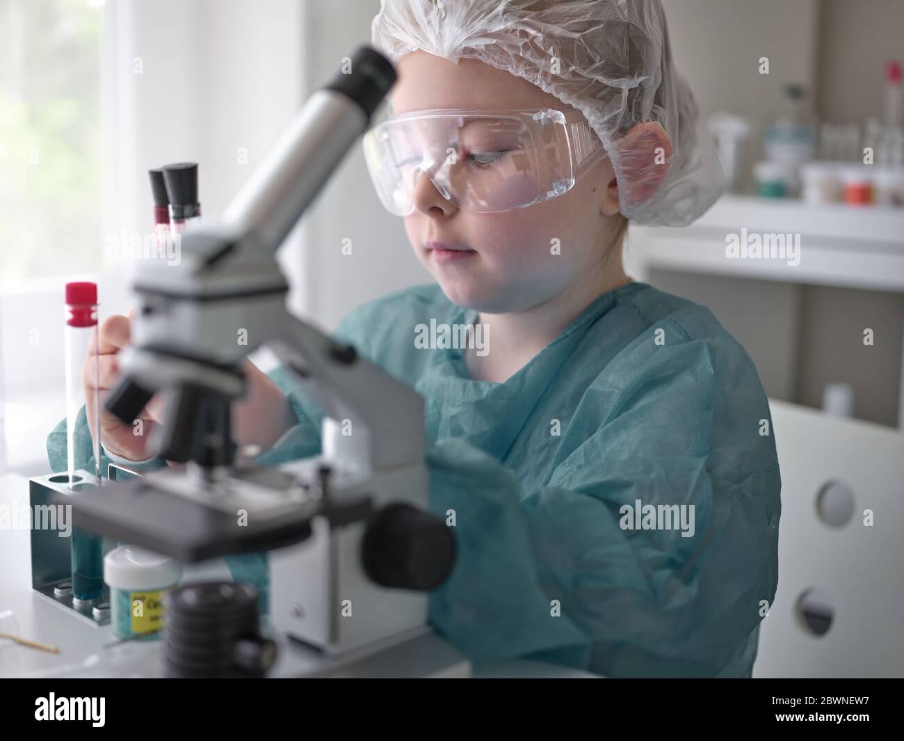 Cute little girl looking into microscope at his desk at home. Young ...