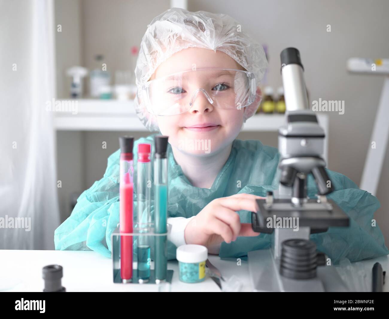 Cute little girl looking into microscope at his desk at home. Young ...