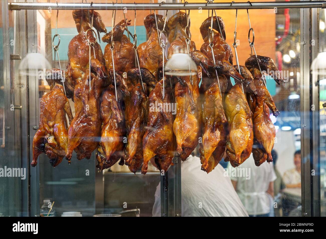 many whole roast duck with heads hanging in a steamy shop window with ...