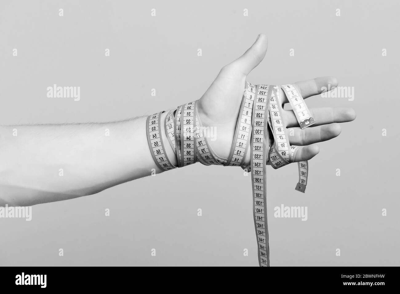 Mans hand wrapped with blue and yellow measuring tapes isolated on ...