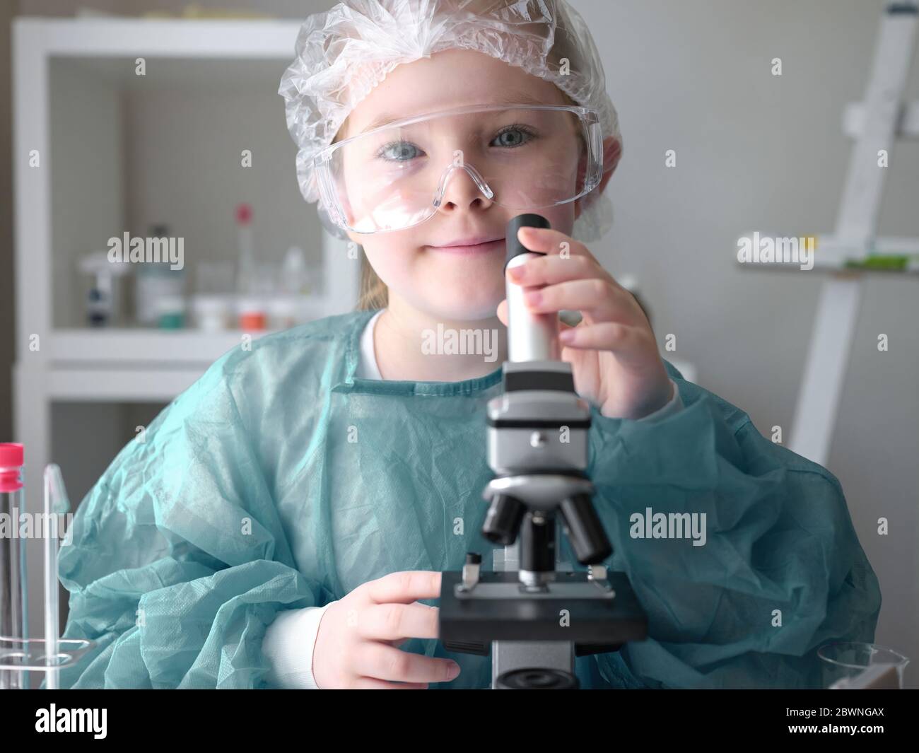 Cute little girl looking into microscope at his desk at home. Young ...
