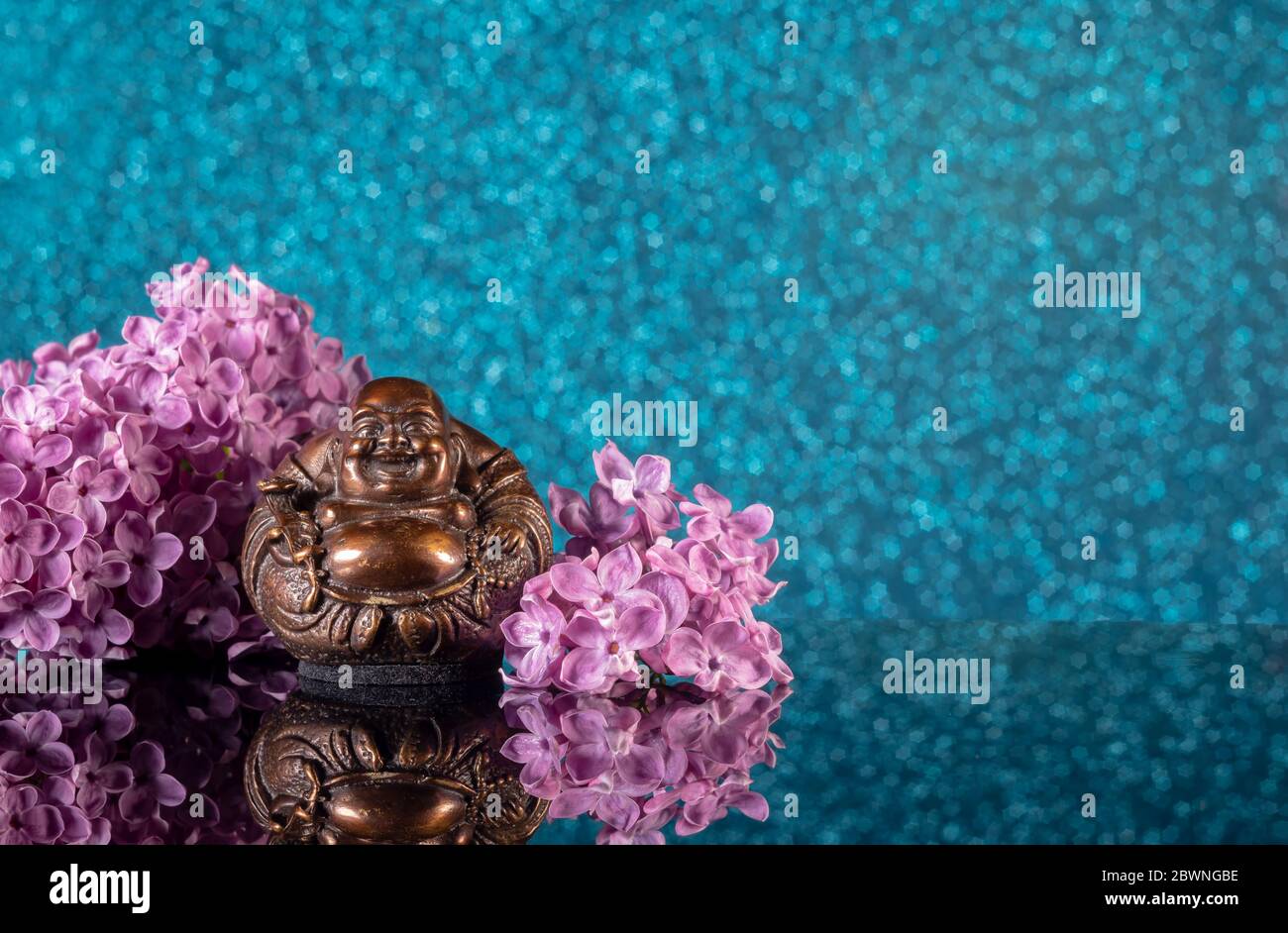 Chinese laughing buddha Hotei or Budai framed by lilac flowers on a ...