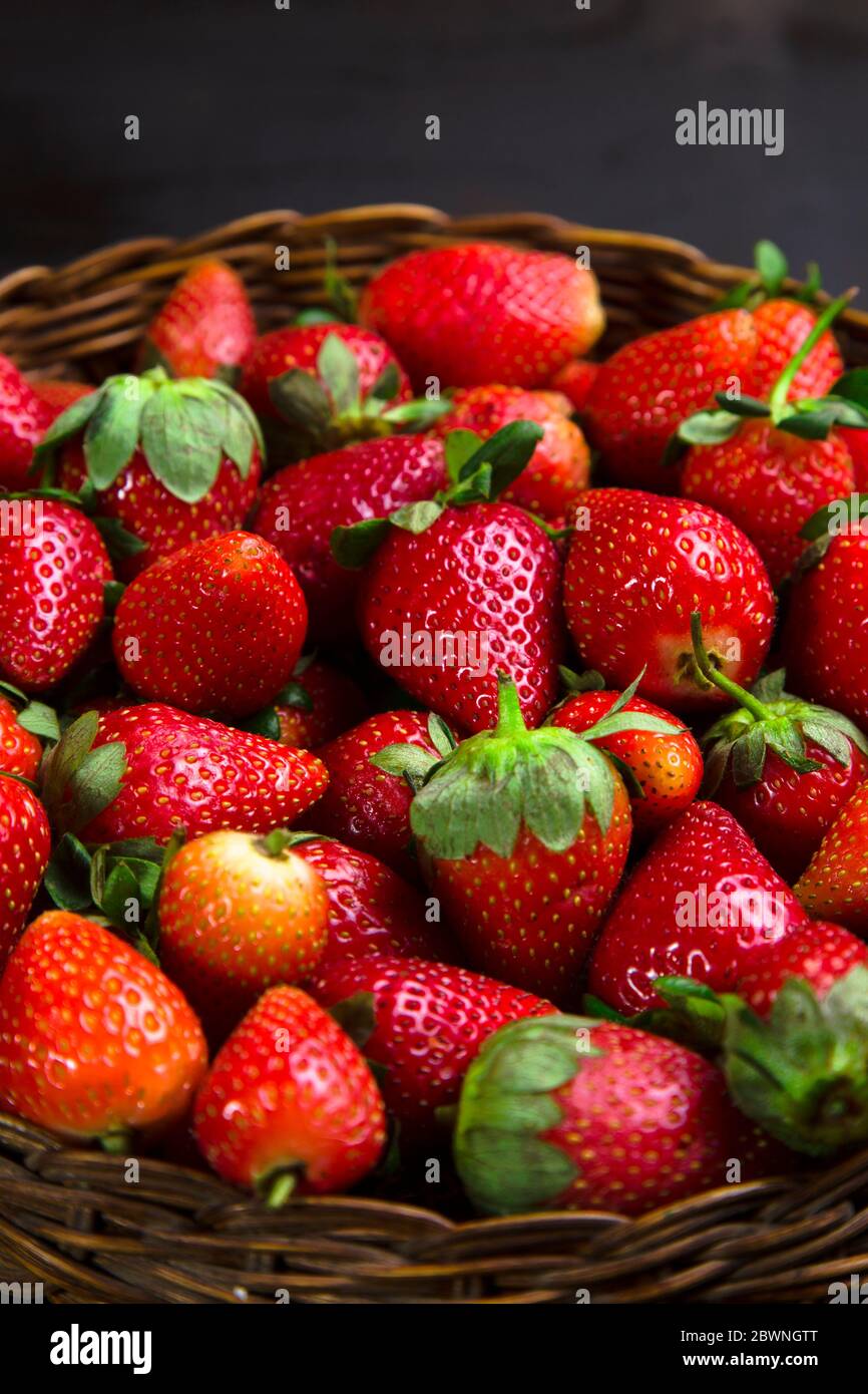 Many strawberries in wicker bowl with black background Stock Photo - Alamy