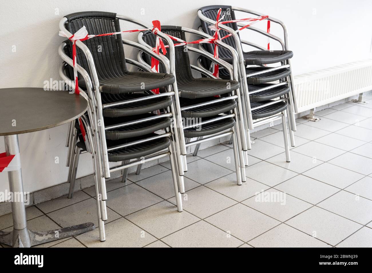Stacks of chairs locked with red and white barricade tape in an empty ...