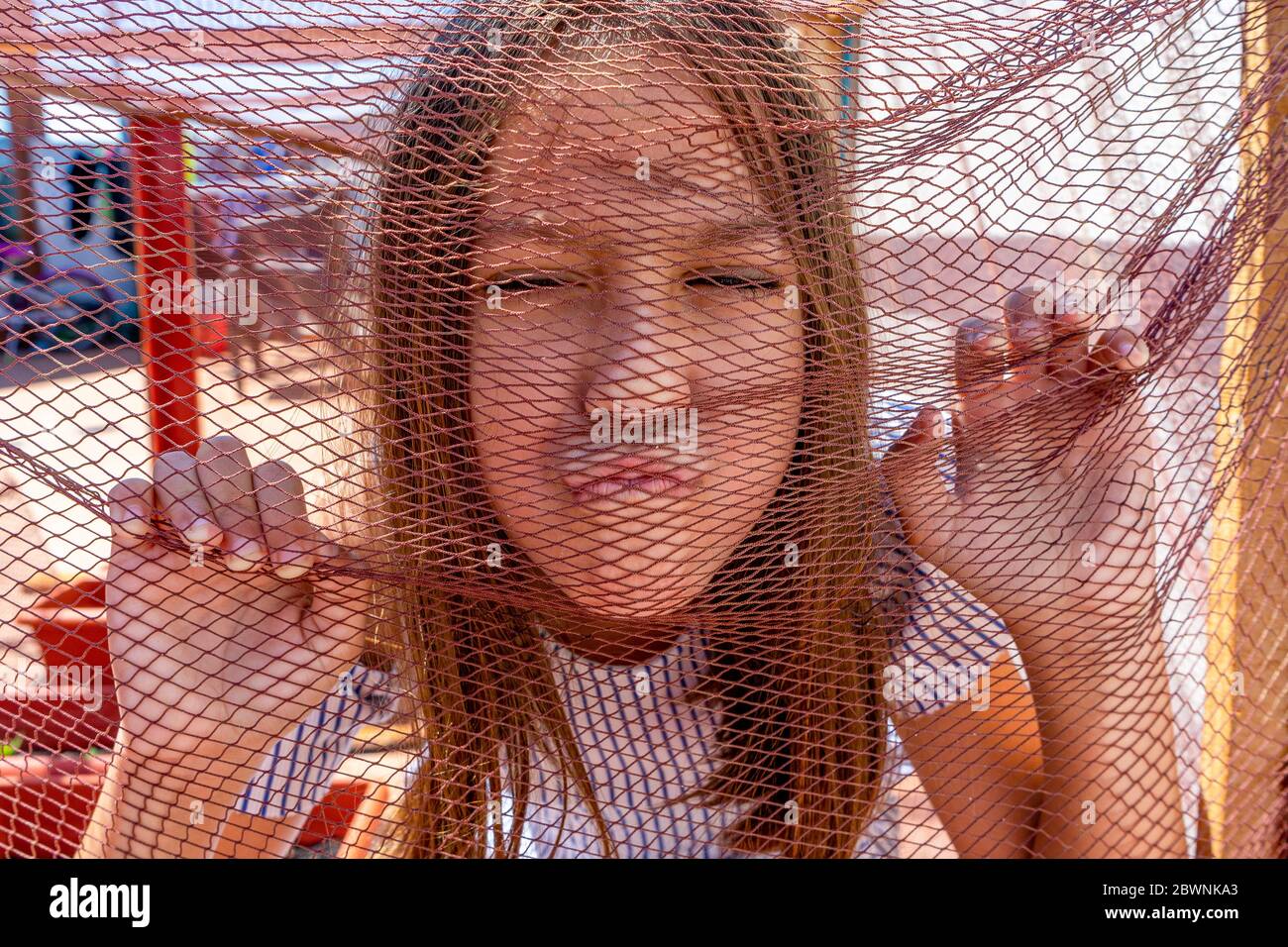 Pretty little girl dressed in a white and blue striped dress locked in ...