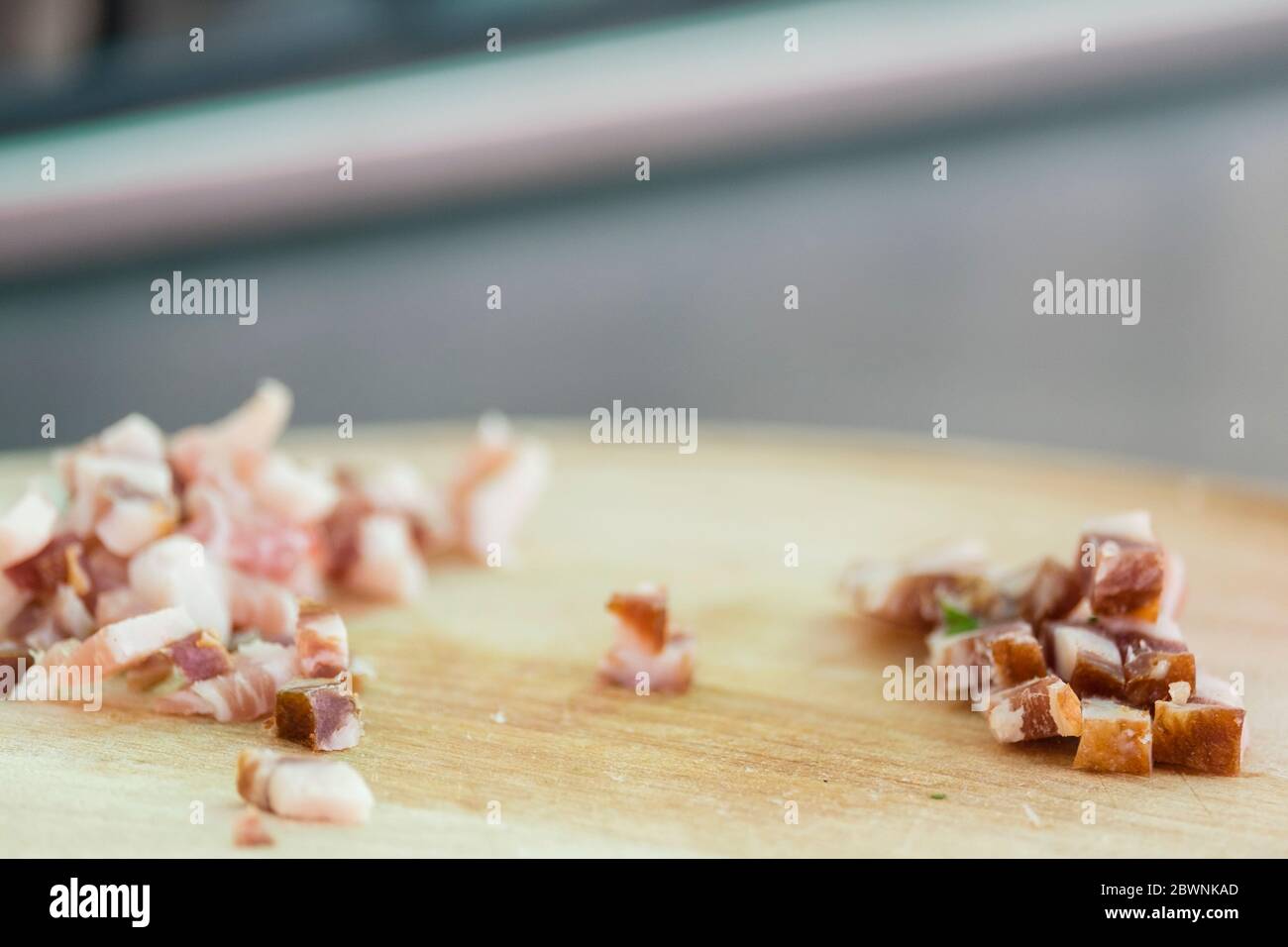 Close-up selective focus of chopped pancetta on wooden cutting board ...