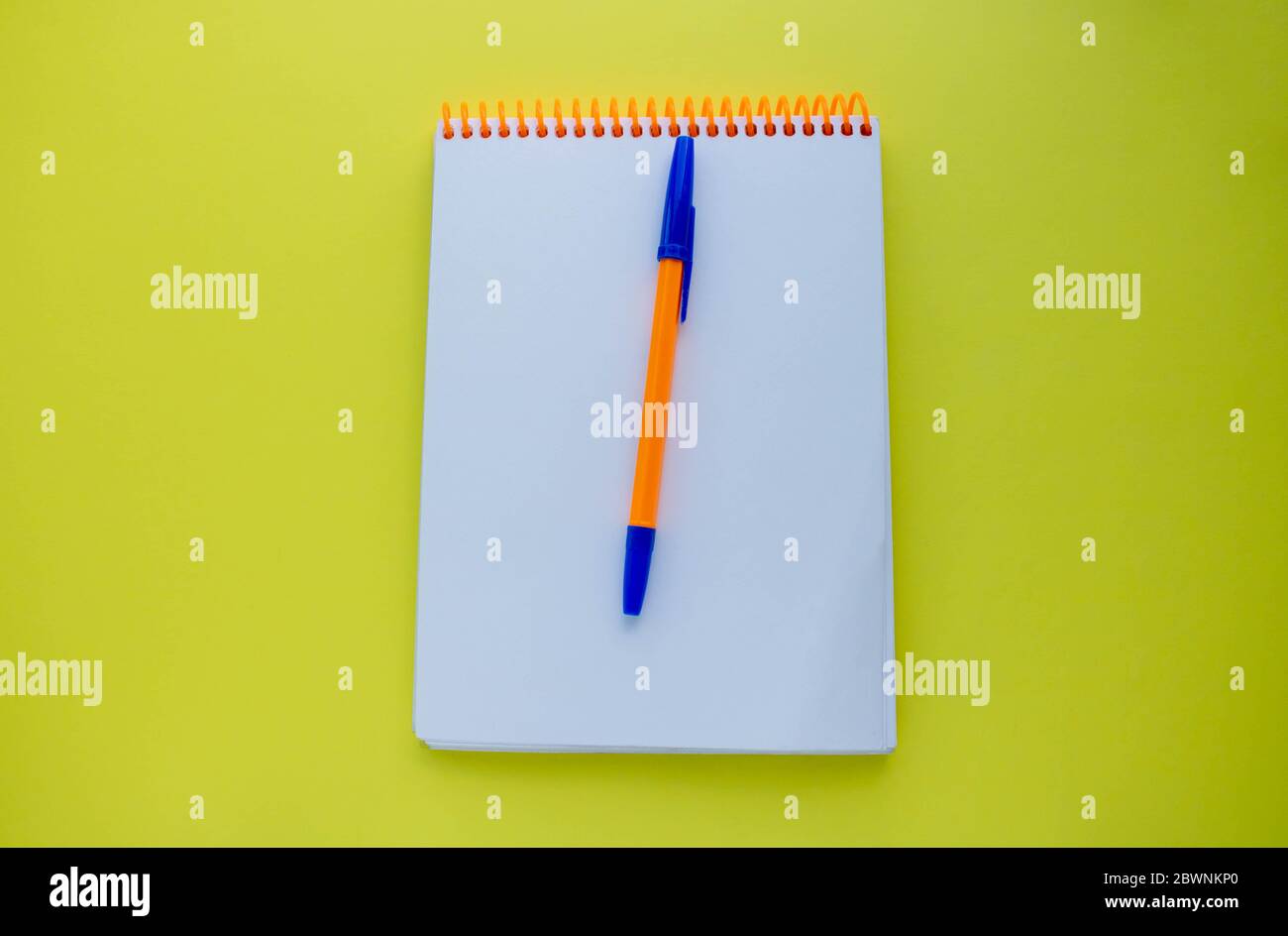 Notepad with an orange spiral and an orange pen, on a yellow background ...