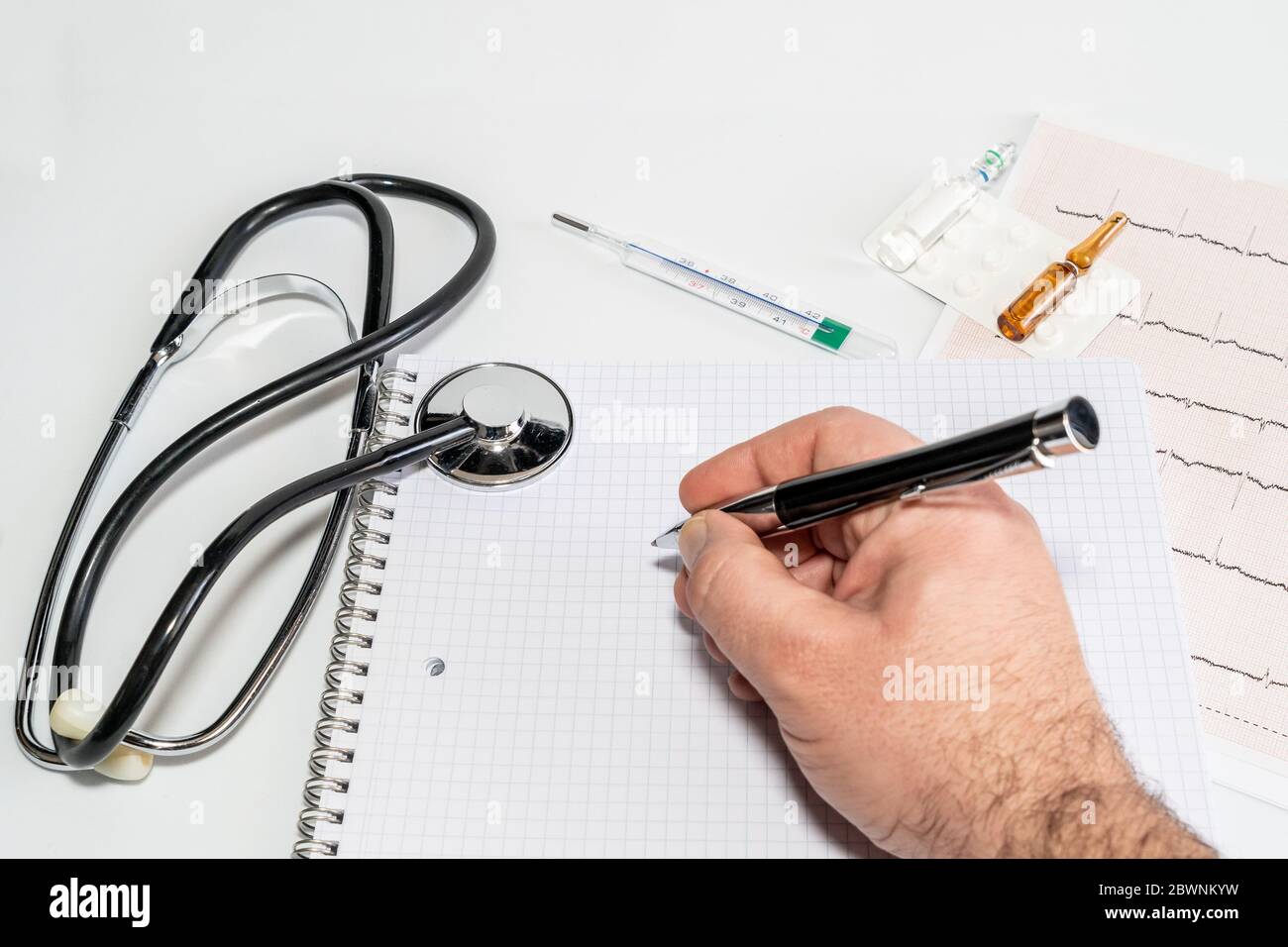 Hand of cardiologist doctor writing the diagnosis on block notes after ...