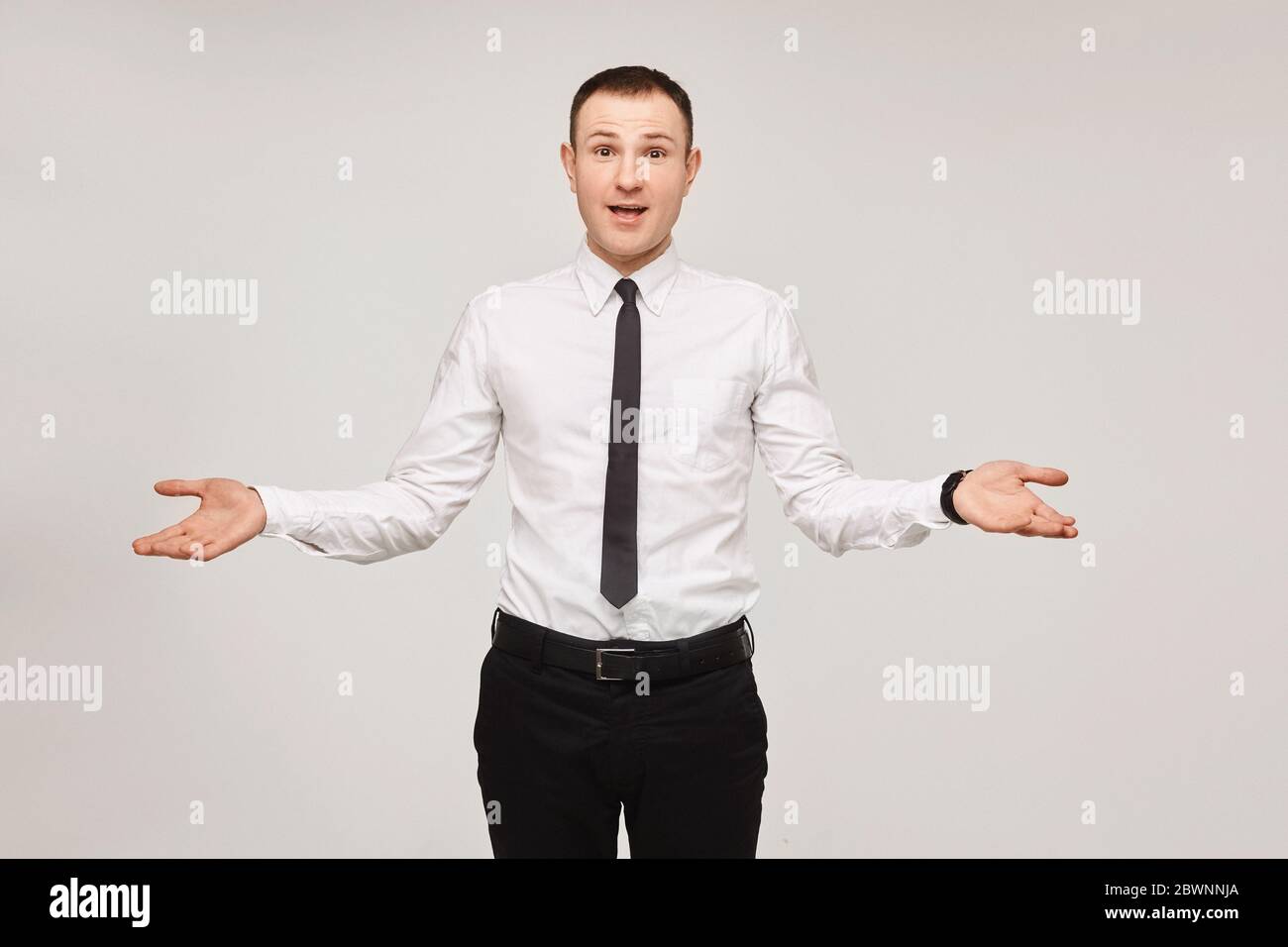 Young amazed man in a white shirt and black tie with arms wide apart at ...