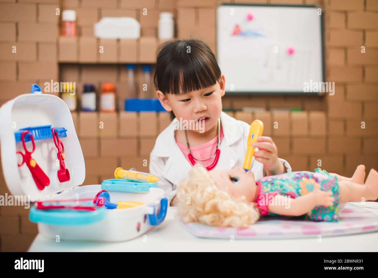 toddler girl pretend play doctor role at home against white background ...