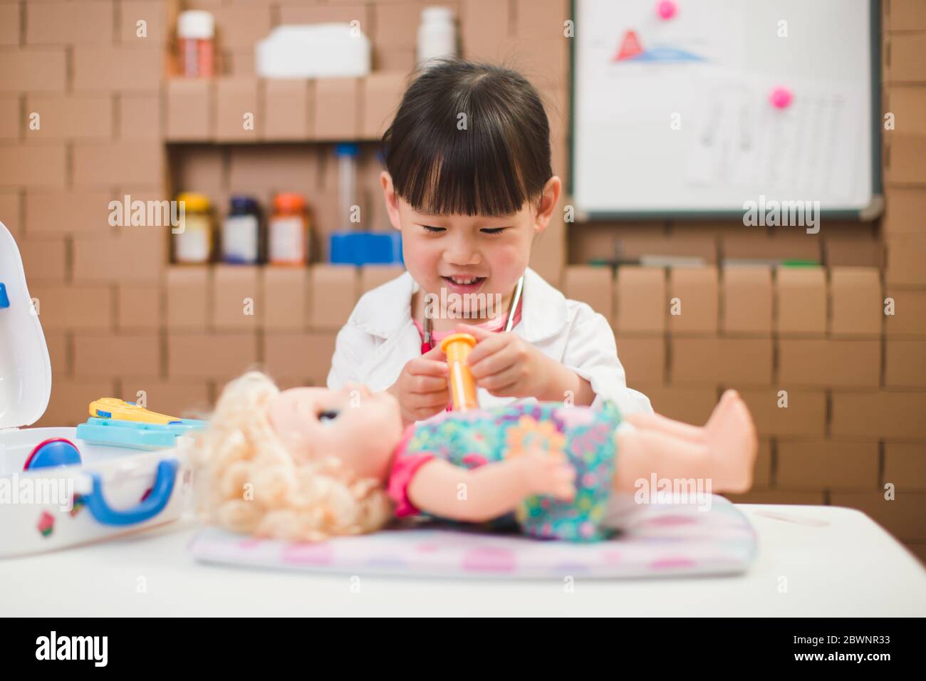 toddler girl pretend play doctor role at home against white background ...