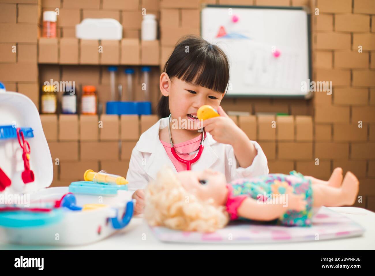 toddler girl pretend play doctor role at home against white background ...