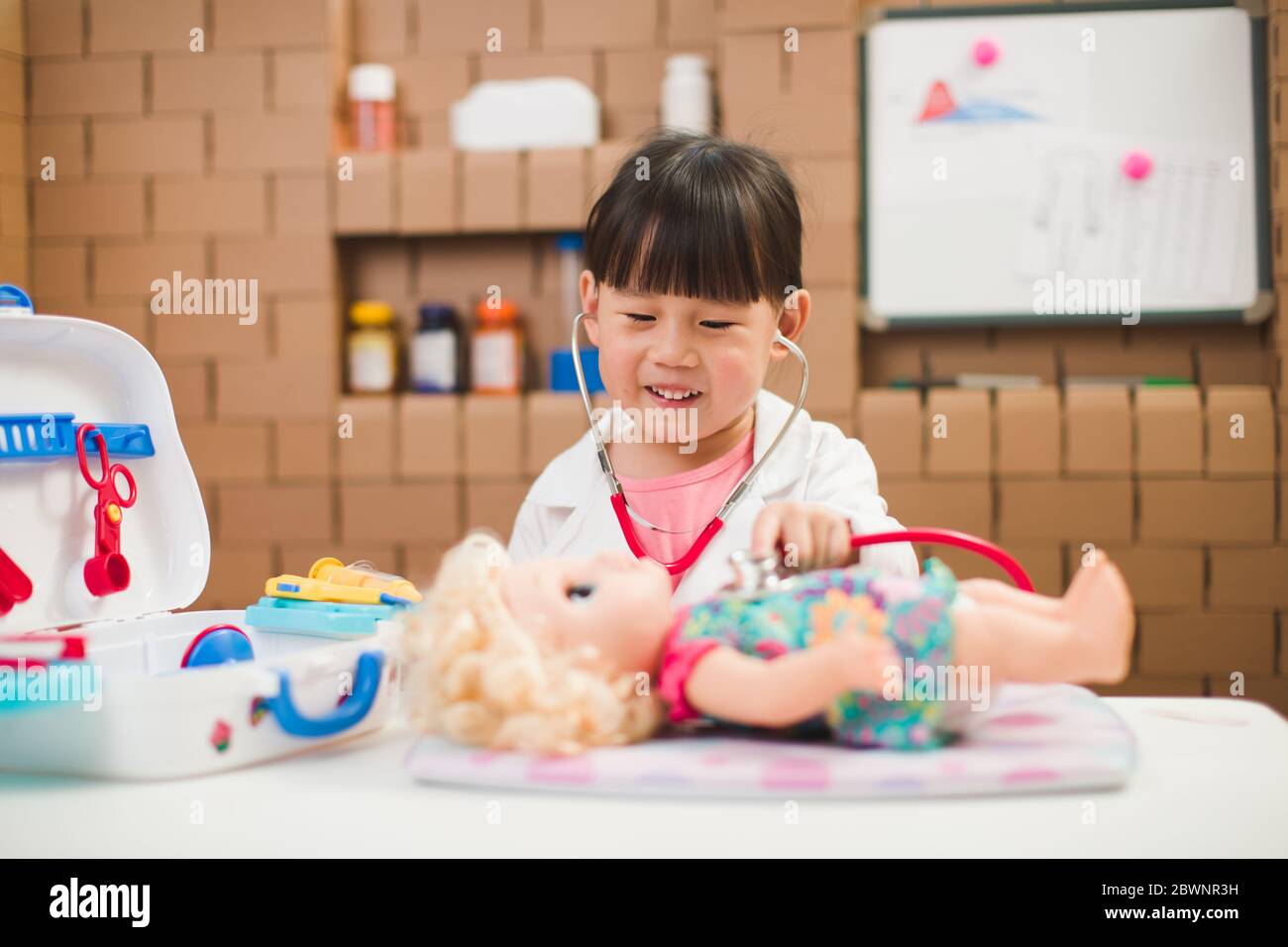 toddler girl pretend play doctor role at home against white background ...